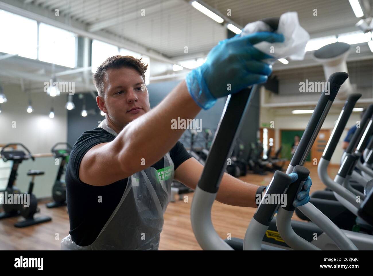 A member of staff cleans the exercise equipment at Nuffield Health ...
