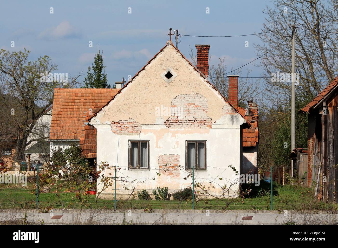 Abandoned small old red bricks suburban family house with cracked facade and two dilapidated ...