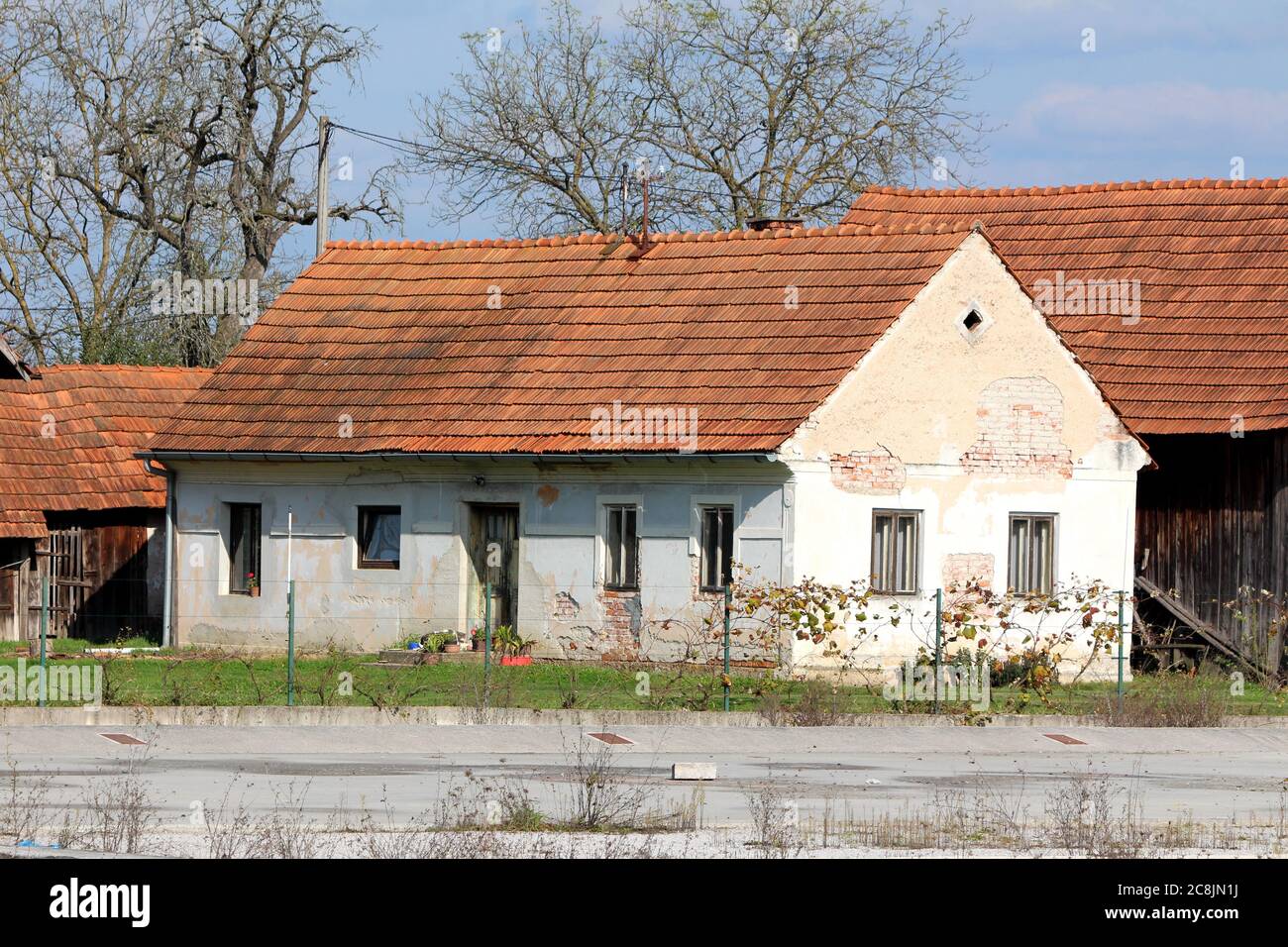 Elongated small old red bricks suburban family house with cracked facade and dilapidated wooden ...