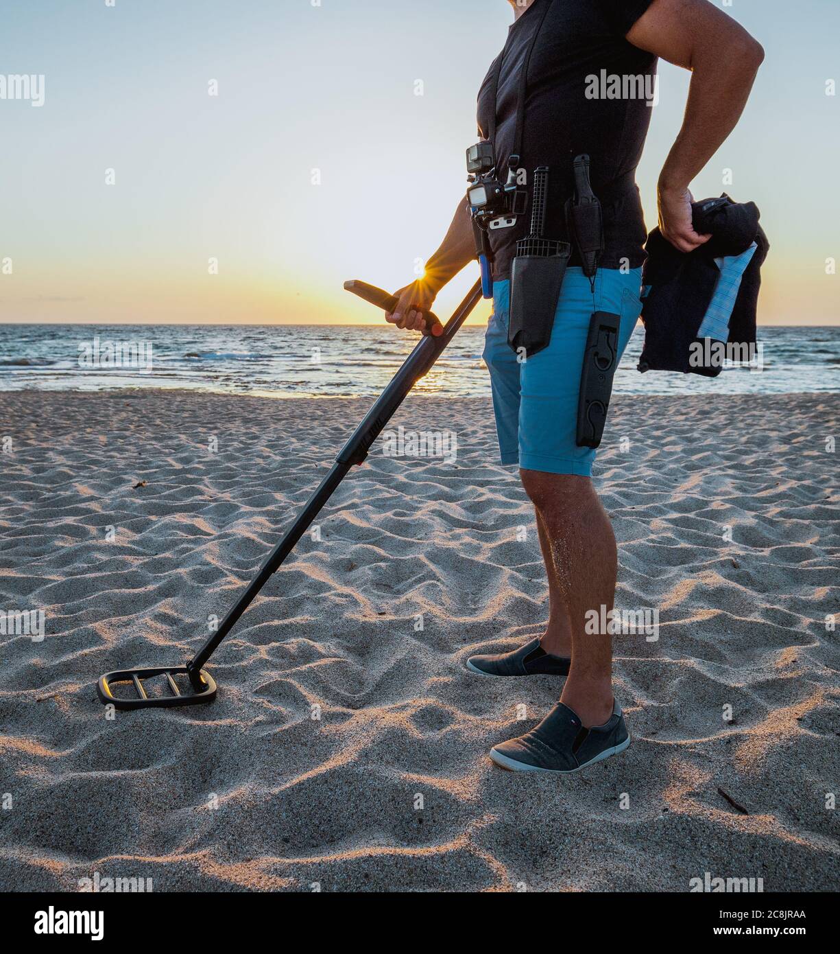 Man with a metal detector on a sea sandy beach Stock Photo - Alamy