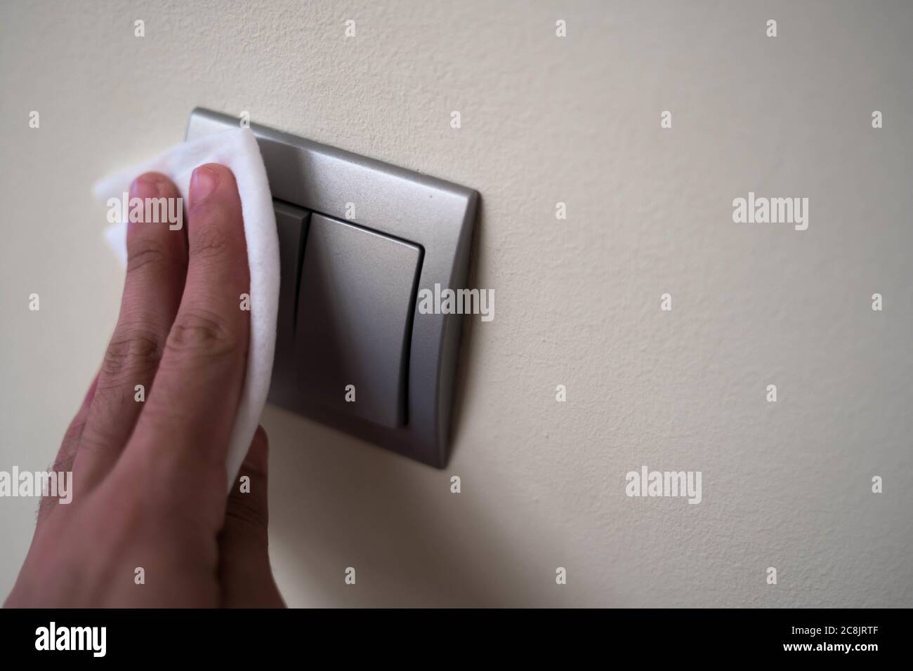 Closeup shot of a human hand cleaning a silver light switch with a wet ...