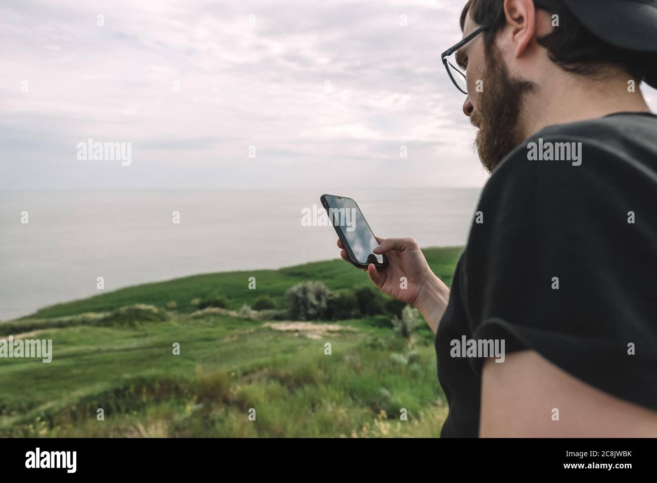 Young bearded caucasian man uses a smartphone on the nature near the ...
