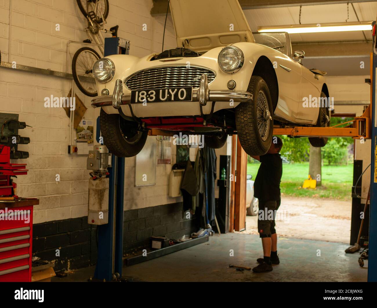 Mechanic under an inspection ramp working on a classic Austin Healey ...