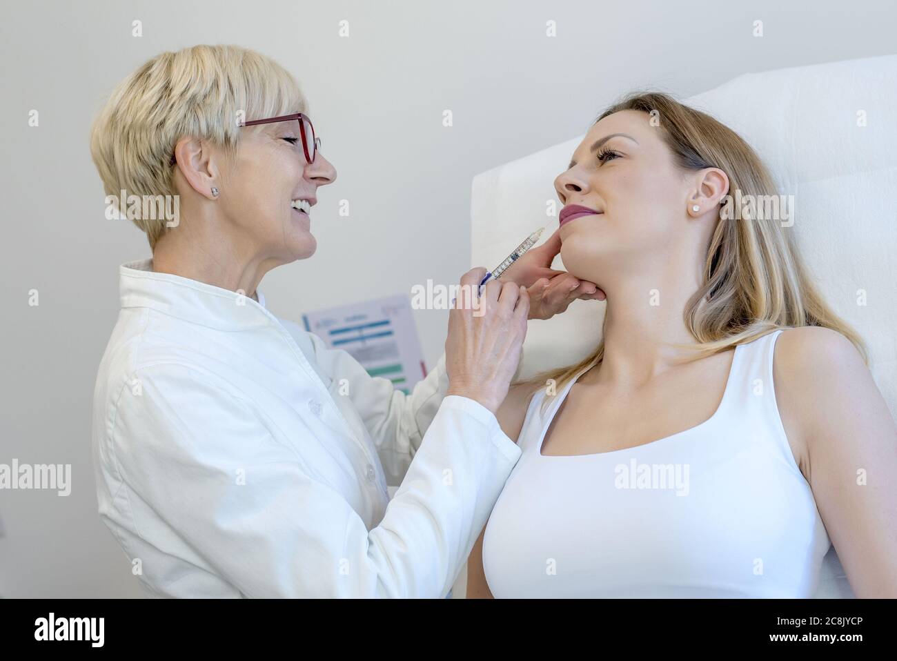 Caucasian female dermatologist injecting fillers into a young patient's ...