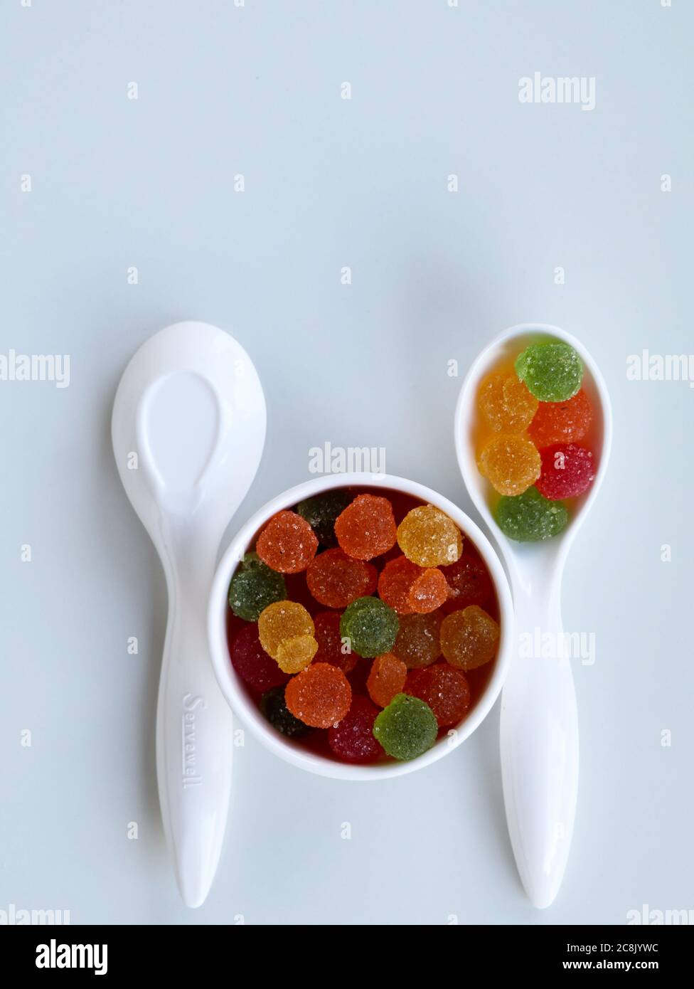 Sweet mixed color jelly candy in a white spoon against white background ...