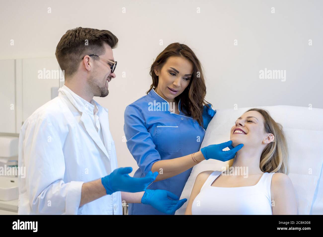 Young caucasian male dermatologist examining a female patient's face ...