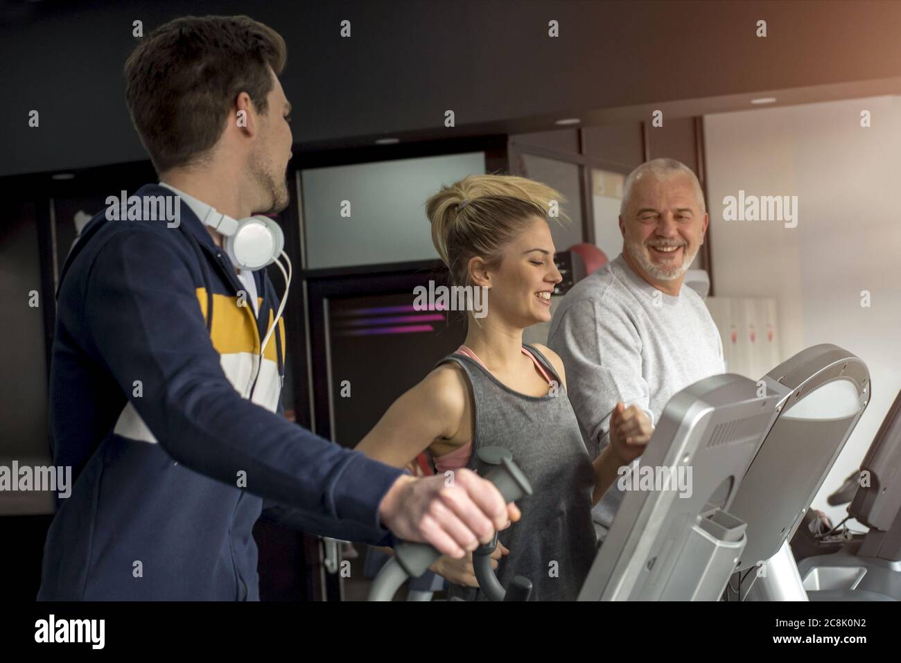 Group of smiling people exercising together on treadmills at the gym ...