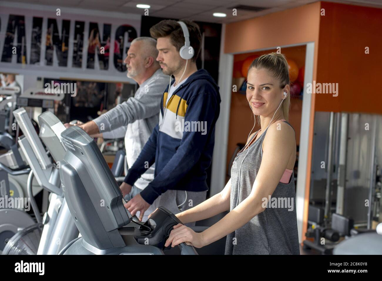 Group of Caucasian friends exercising together on treadmills in a gym ...
