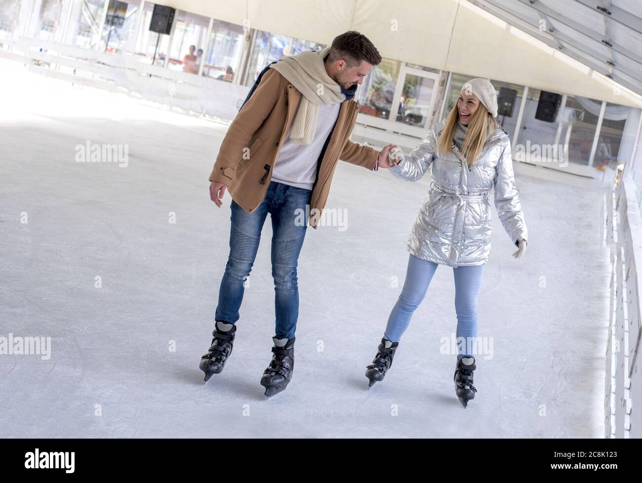 Happy young couple skating outside during the snowy weather - romantic ...