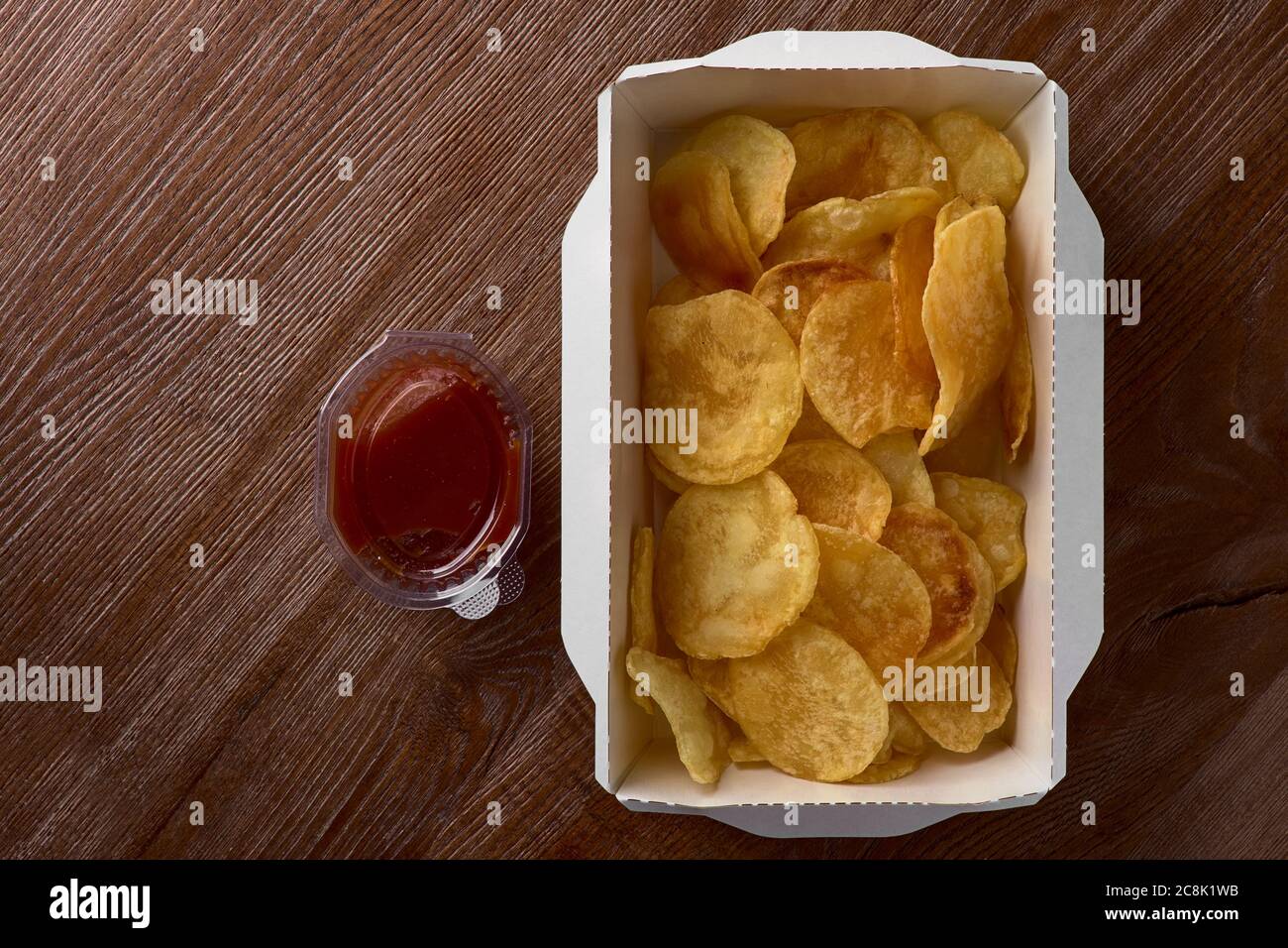 Delicious sweet potato chips with ketchup on a carton box take away ...