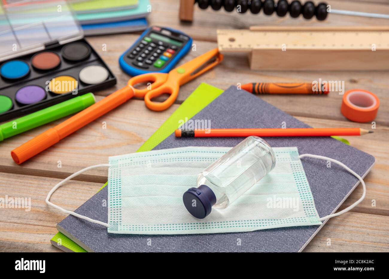 School supplies, medical protective mask and sanitizer gel on wooden ...