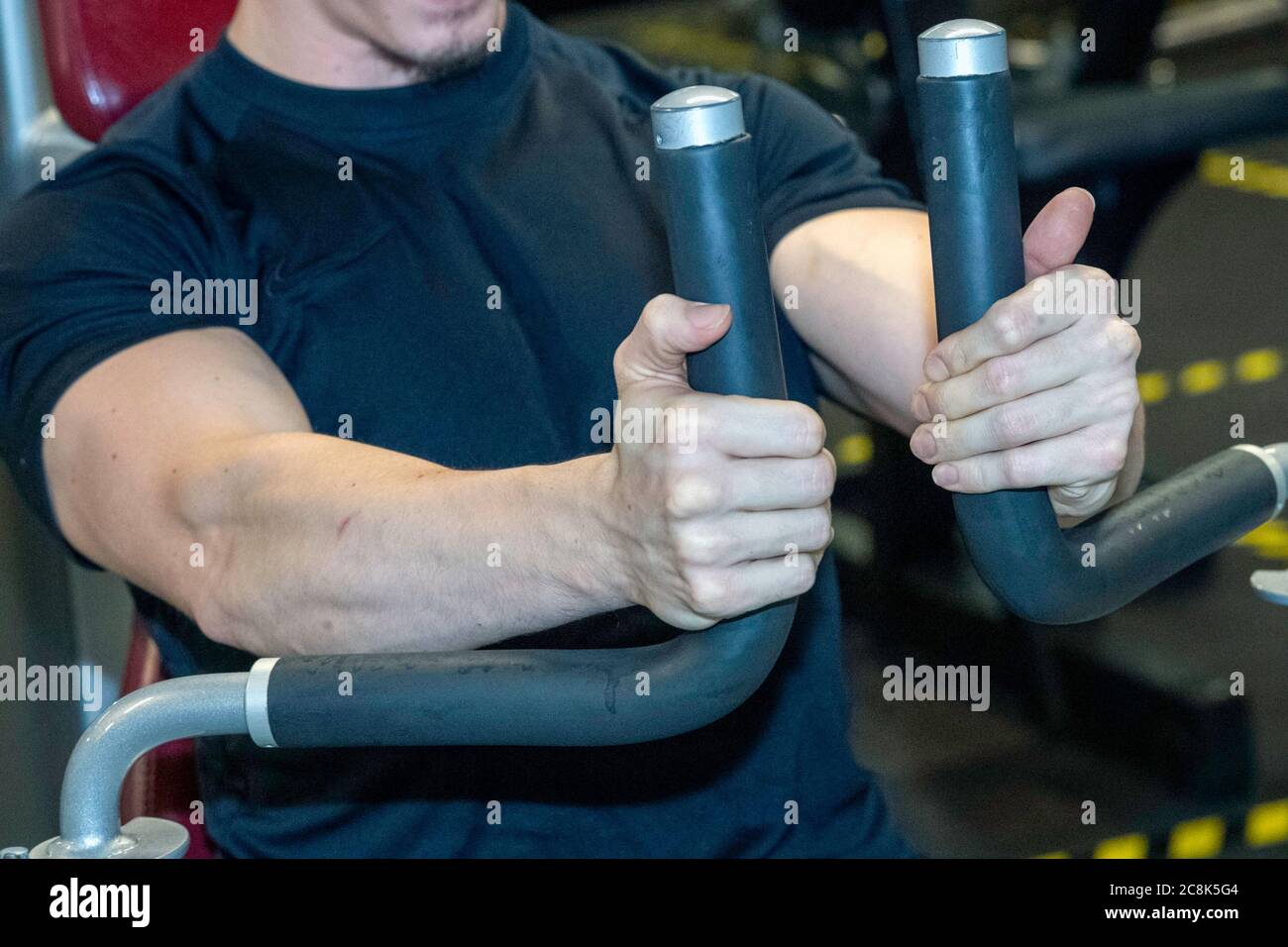 Man's arms on an exercise machine in gym Stock Photo - Alamy