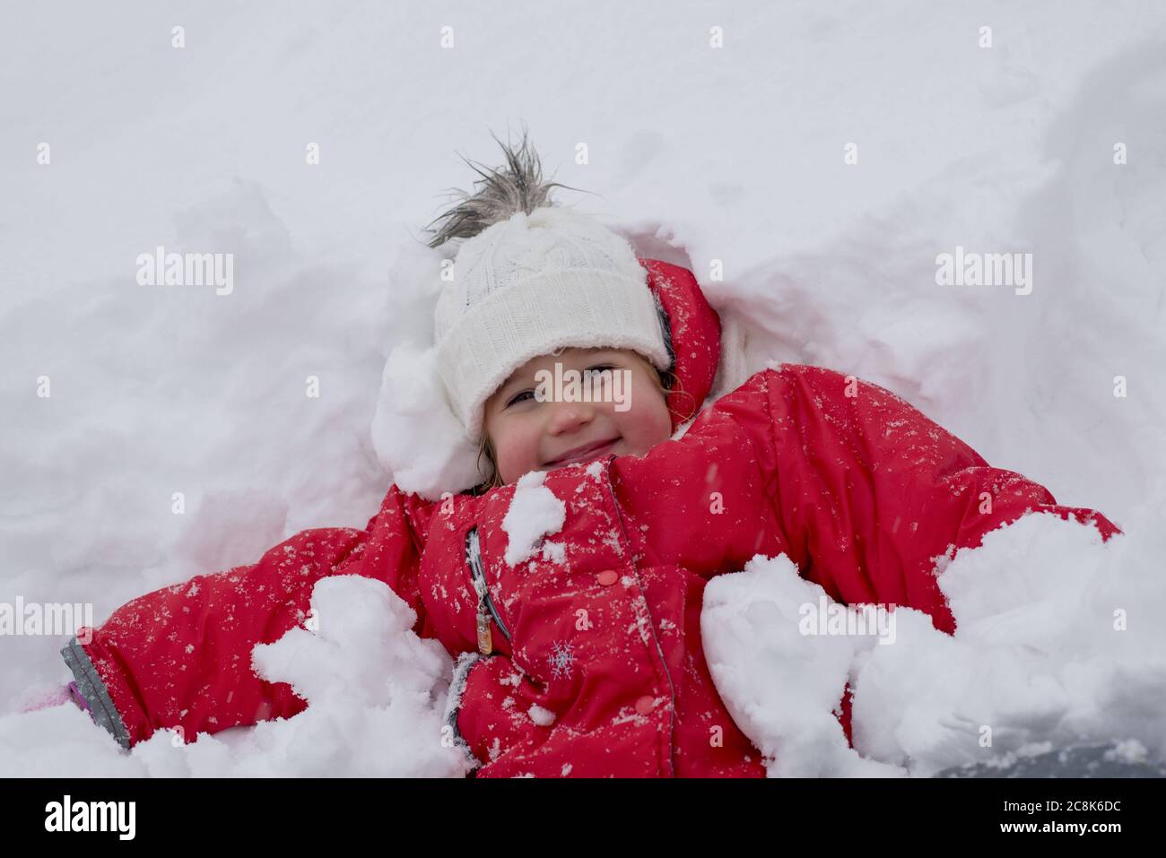 Little Caucasian girl lying on his back in the snow and enjoying the ...