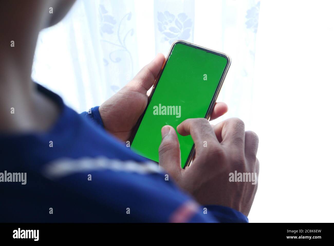 back view of man holding smart phone with green screen Stock Photo - Alamy