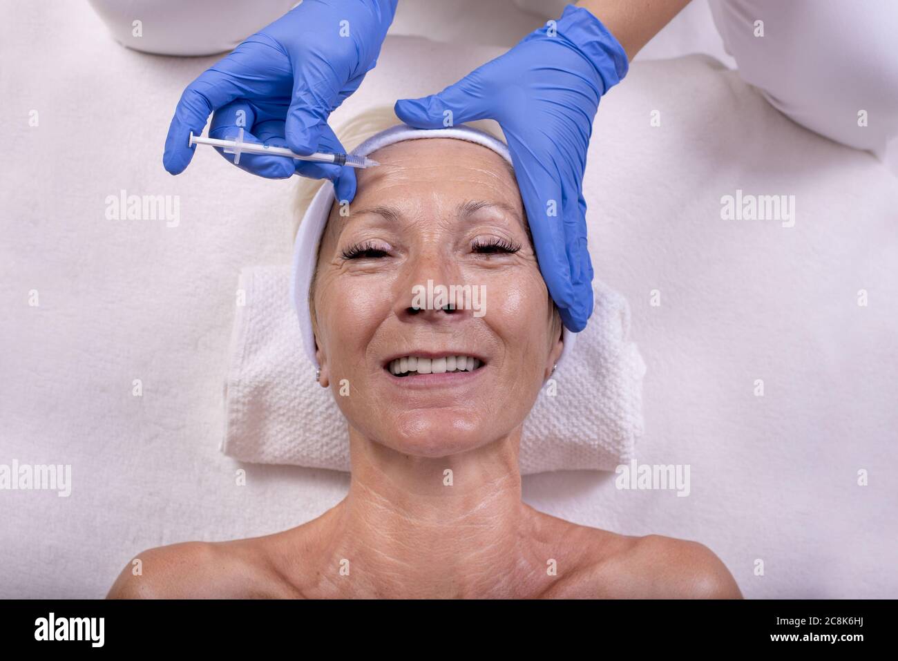 Old woman taking injections by a person wearing blue rubber gloves ...