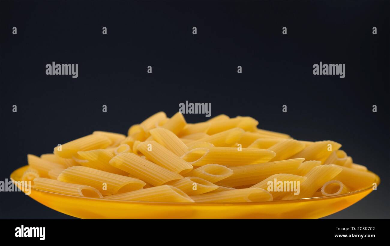 Raw italian penne rigate pasta on black background with copy space ...