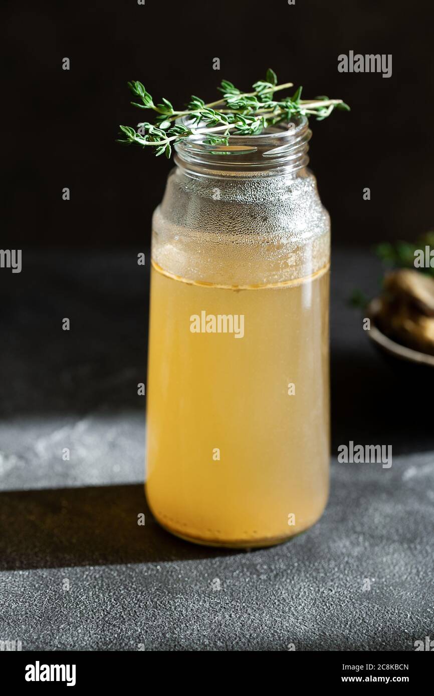 Fresh vegetable bone broth in glass jar with herb on dark gray ...