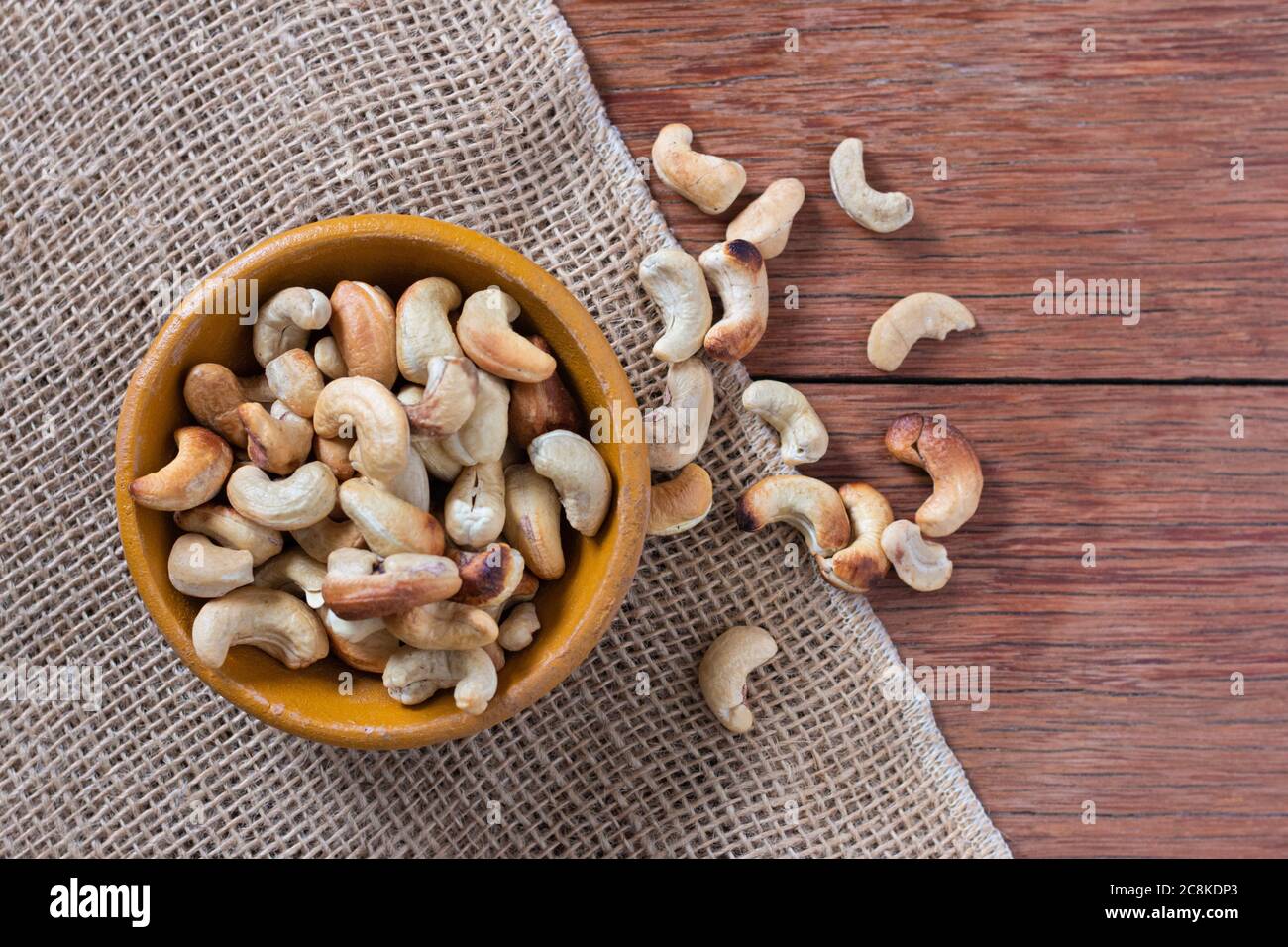 Tasty cashew nuts in bowl on wooden table. Space for text. Top view ...