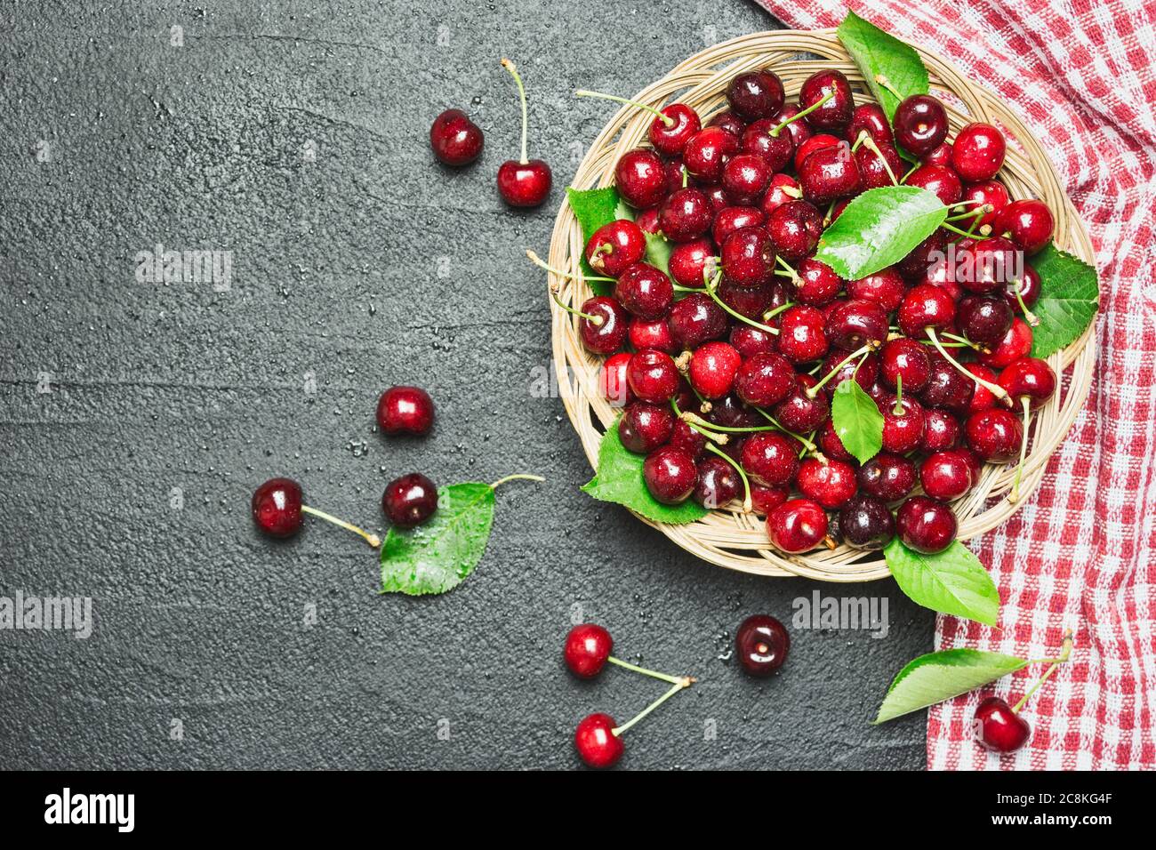 Juicy ripe cherries in wooden bowl on black concrete table, top view ...