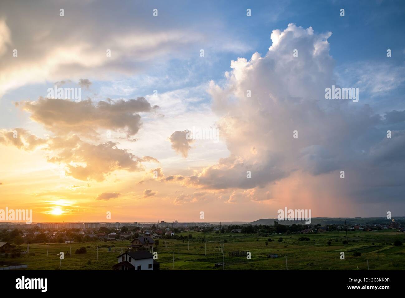 Dramatic sunset landscape of rural area with stormy puffy clouds lit by ...