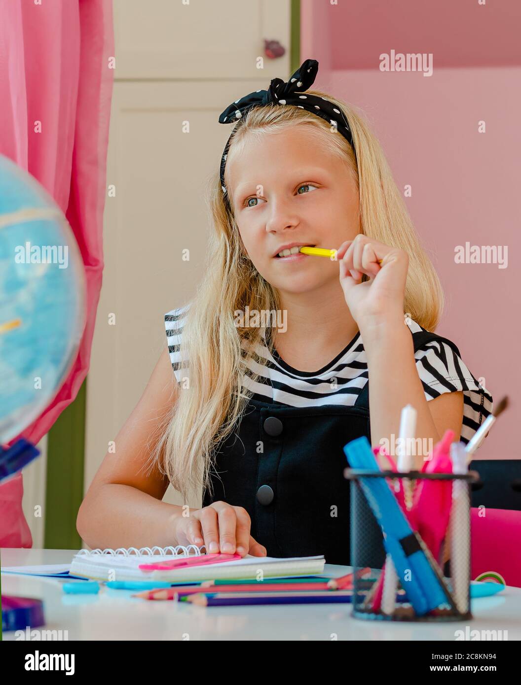 Caucasian blonde school girl is dreaming or thinking while studying ...