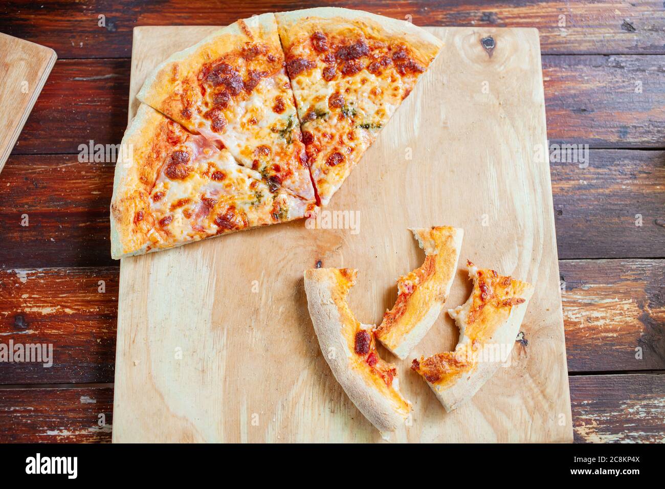 Pizza on a wooden tray. Dry crusts of the edge of the pizza bitten lie ...