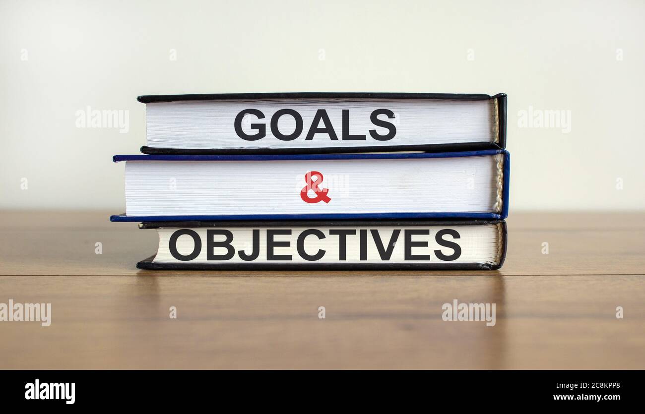 Books with text 'goals and objectives' on beautiful wooden table. White ...