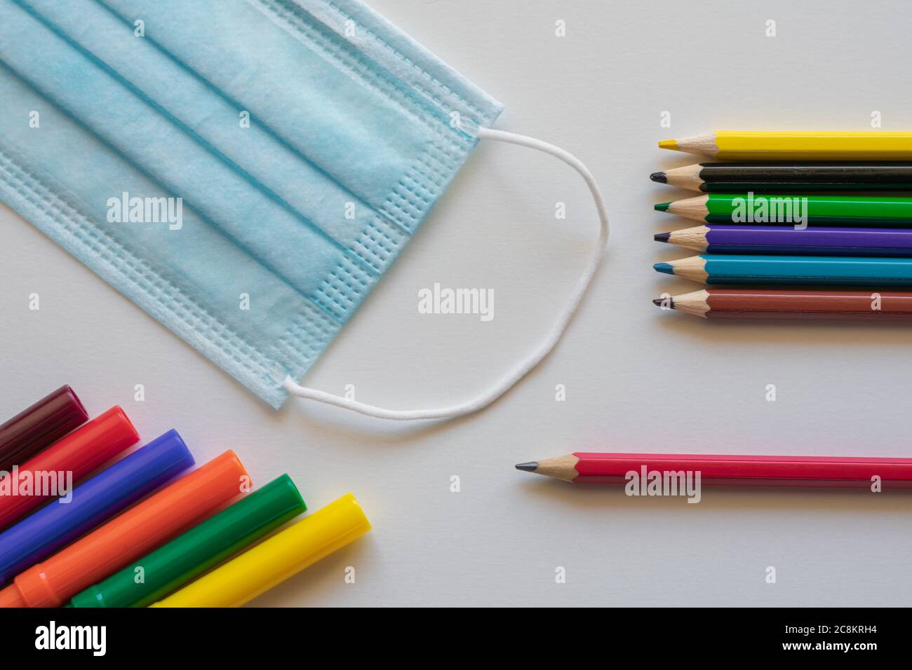 Markers and colored pencils next to a mask, mandatory in many countries ...