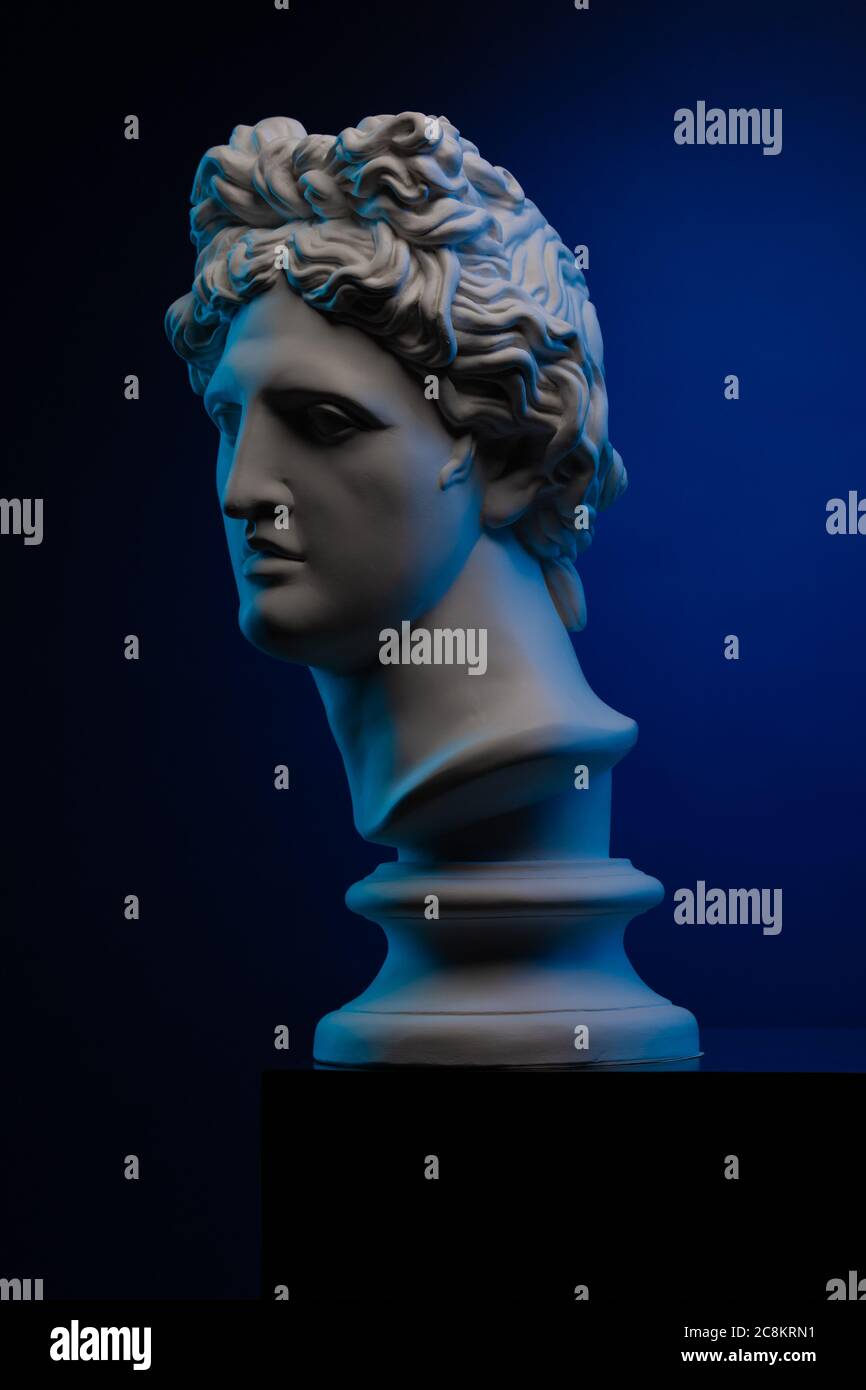 Statue of a bust of Apollo's head in blue local light on a blue black ...