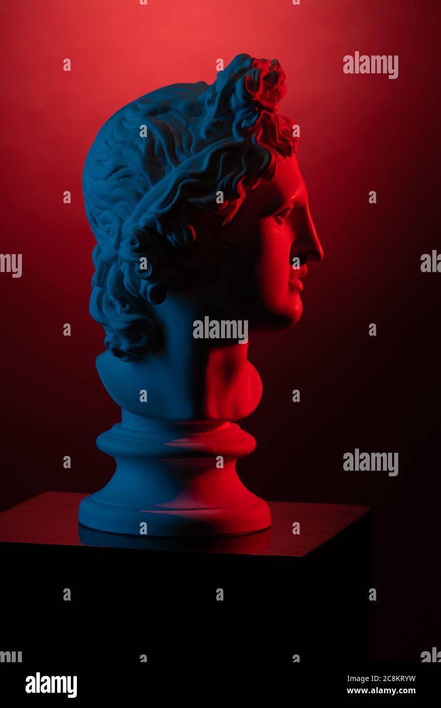 Plaster statue bust of Apollo Belvedere in red and blue light on a red ...