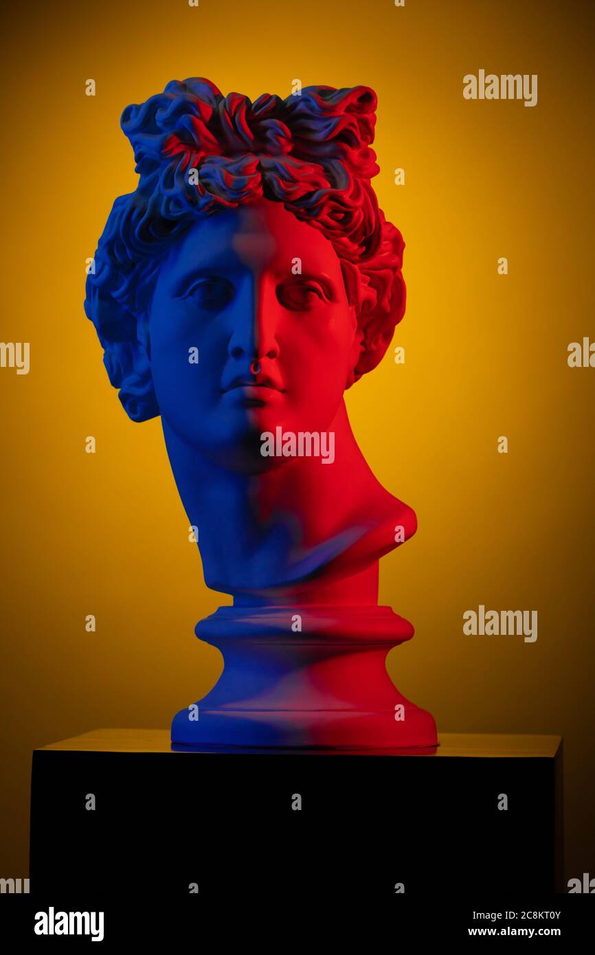 Plaster statue of a bust of Apollo Belvedere in red and blue light on a ...