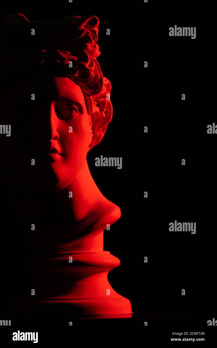 White plaster statue of a bust of Apollo Belvedere in red light on a ...
