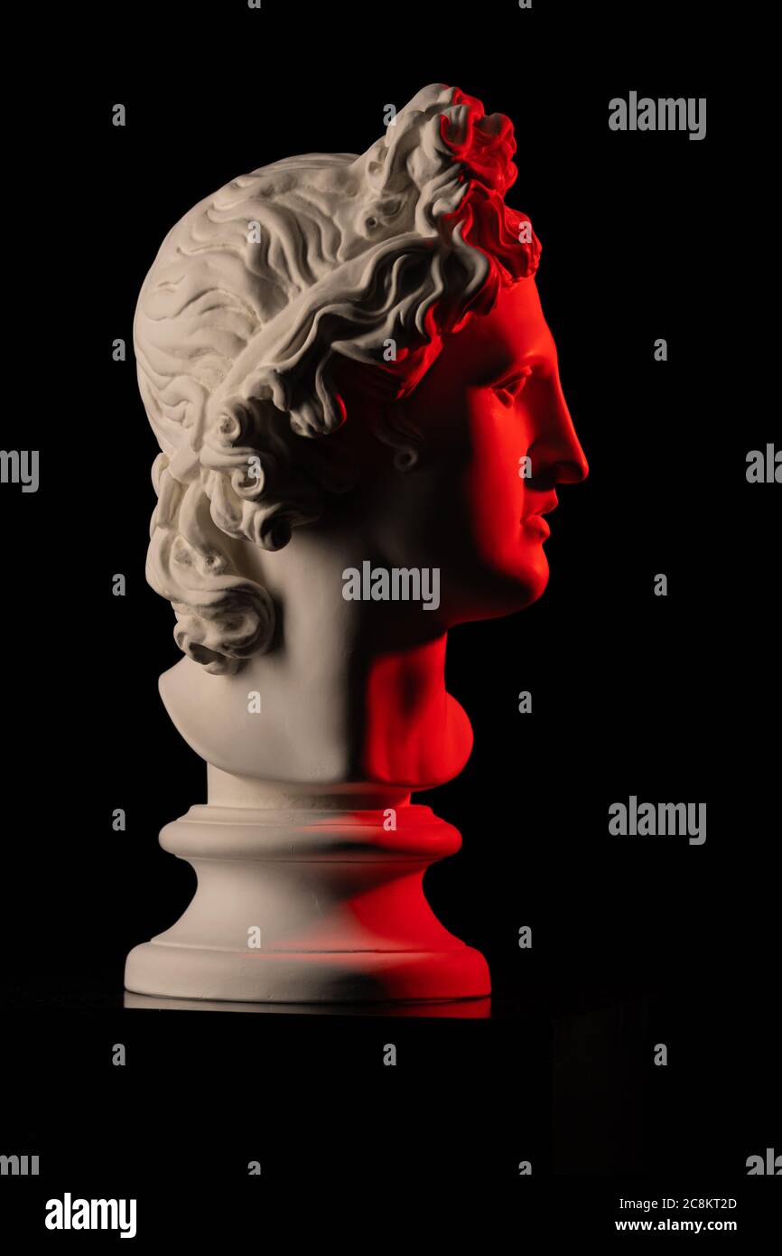 White plaster statue of a bust of Apollo Belvedere in red light on a ...