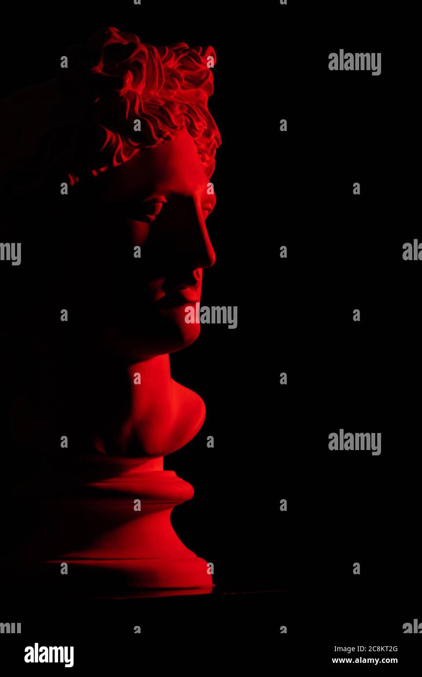 White plaster statue of a bust of Apollo Belvedere in red light on a ...