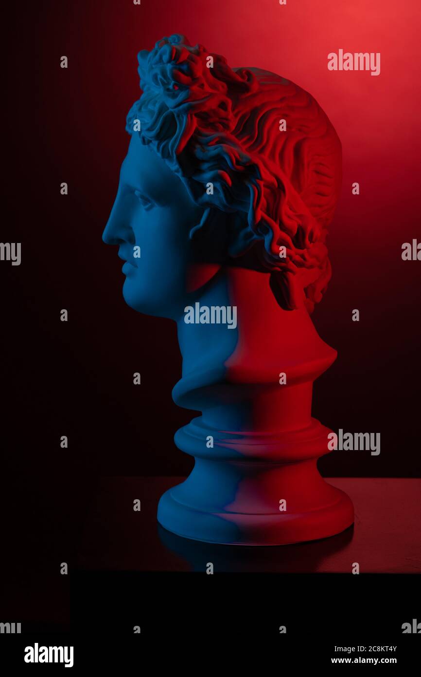 Plaster statue bust of Apollo Belvedere in red and blue light on a red ...