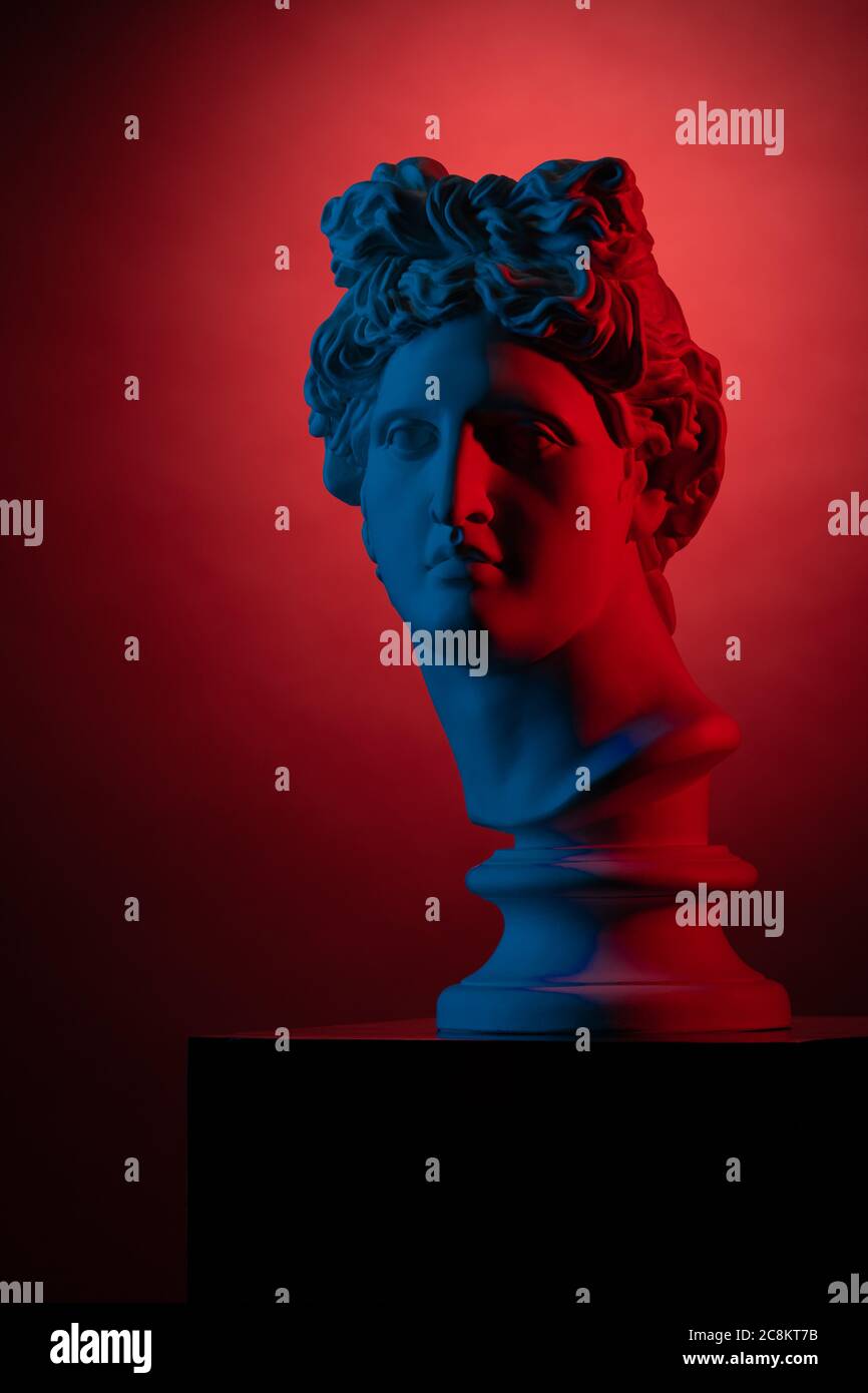 Plaster statue bust of Apollo Belvedere in red and blue light on a red ...