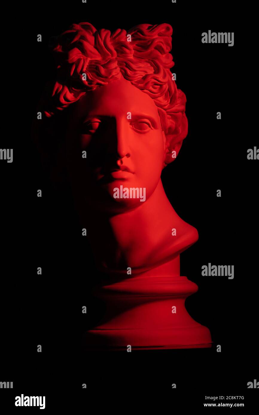White plaster statue of a bust of Apollo Belvedere in red light on a ...