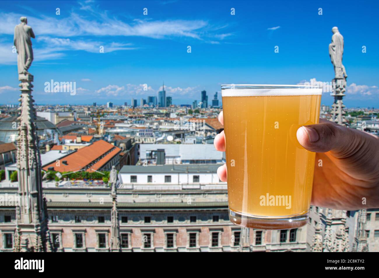 Man holding glass of light beer with view from Milan Cathedral (Duomo ...