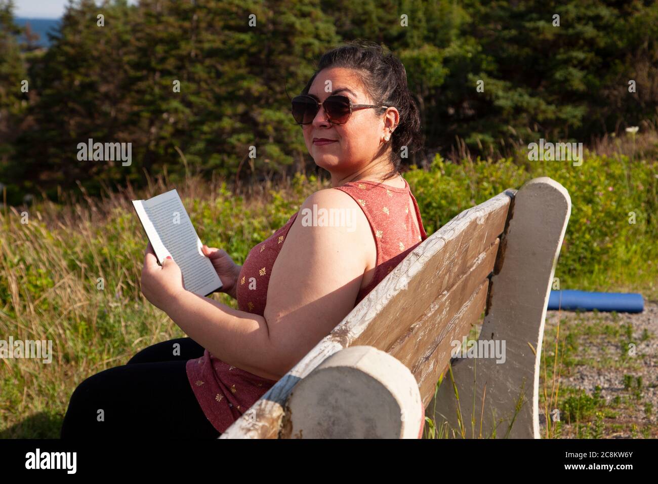 woman outside content with a book looking at the camera Stock Photo - Alamy