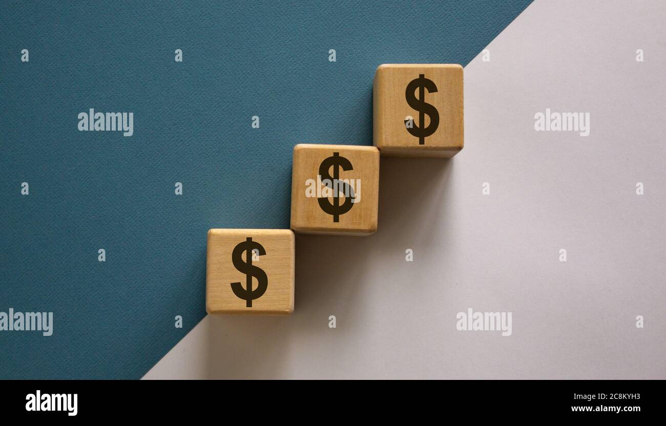 Wood cubes with dollar sign stacking as step stair on paper blue and ...