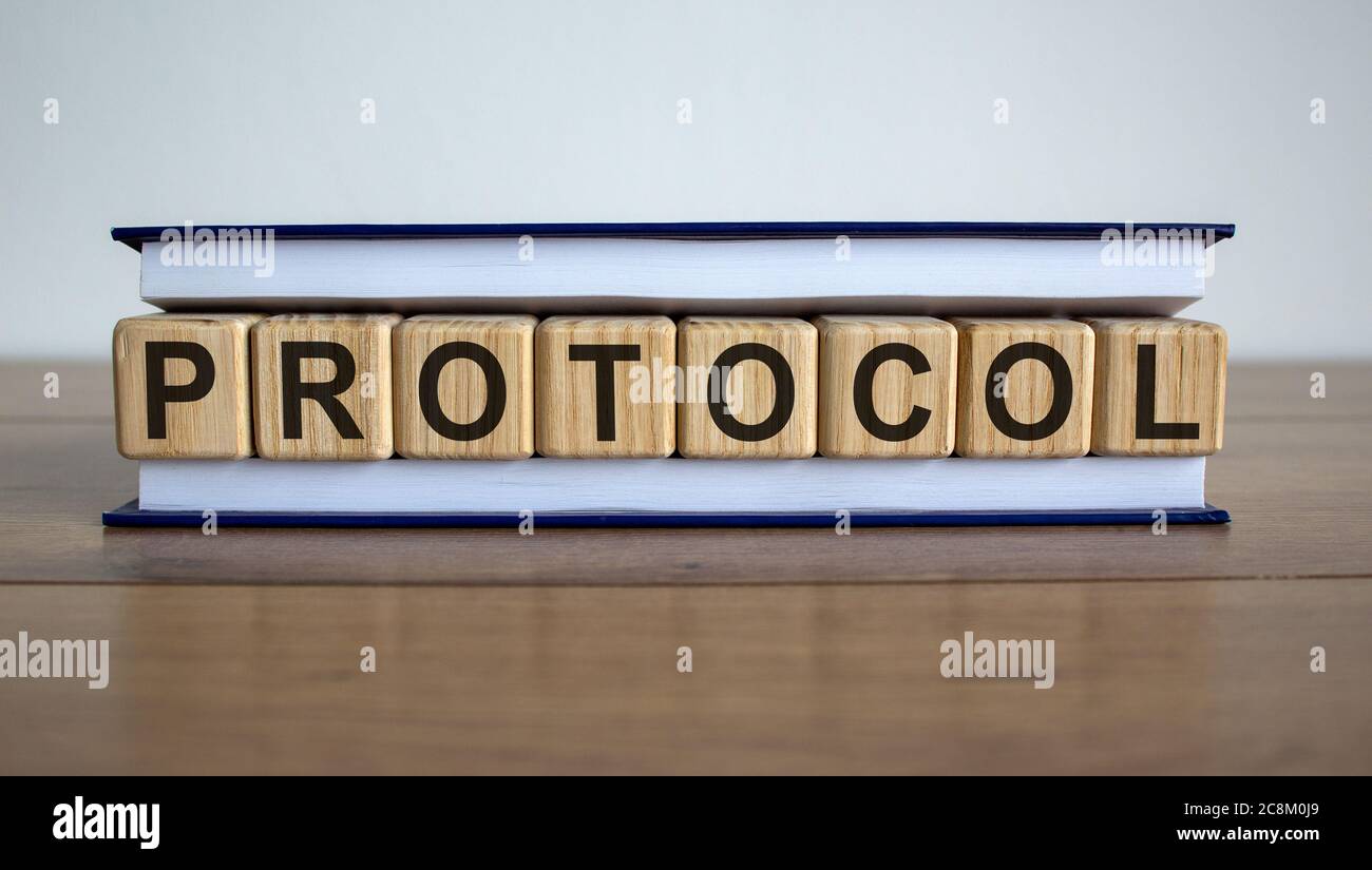 Concept word 'protocol' on wooden circles between pages of a book on a ...