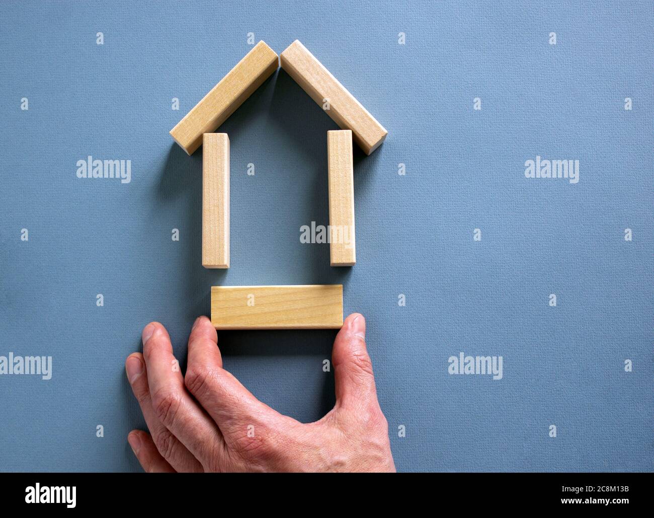 Male hand builds a model of a wooden house from wooden blocks. Copy ...
