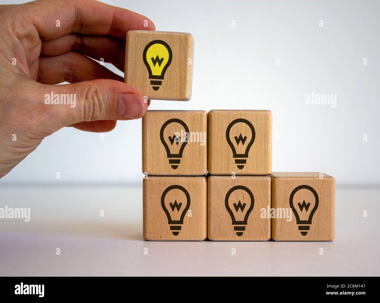 Business concept. Male hand placing a cube with light bulb sign on top ...
