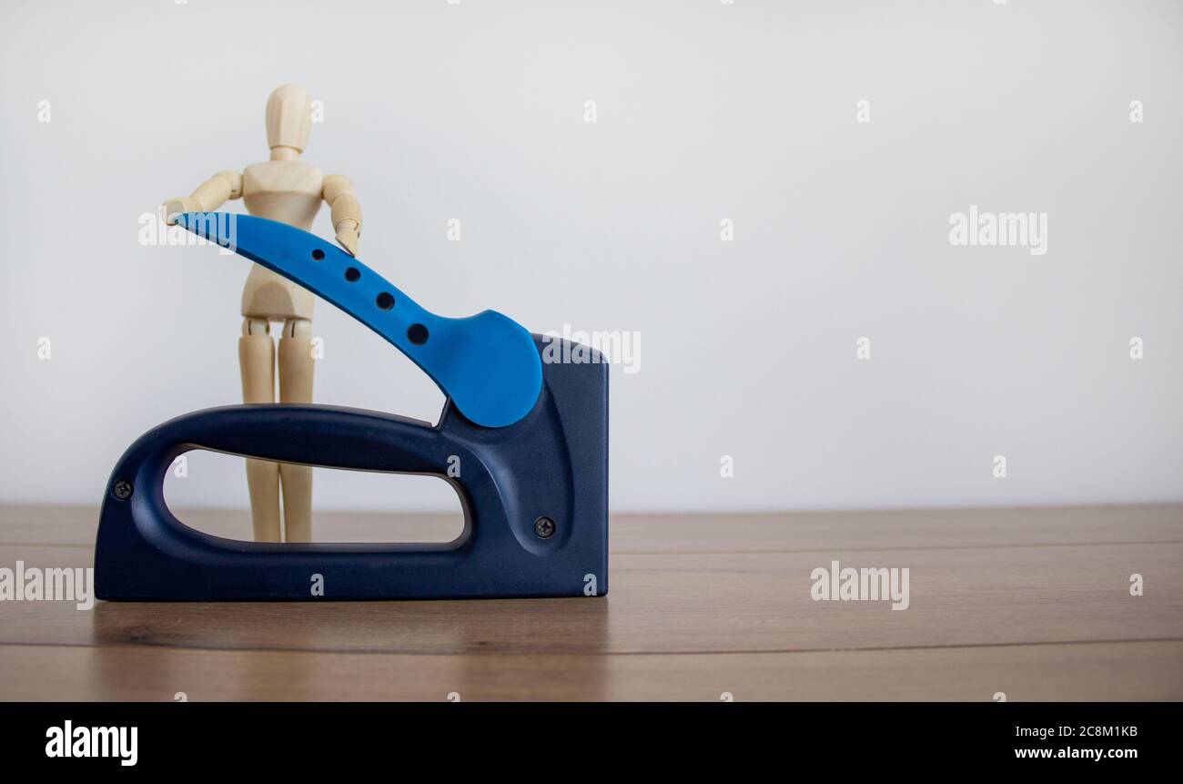 A construction stapler on a wooden table. Wooden model of human ...