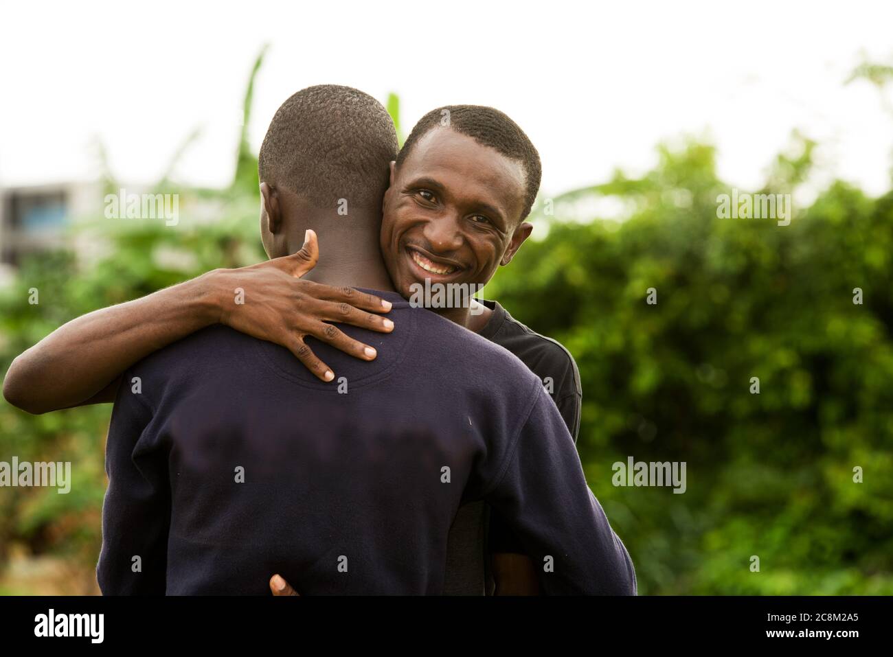 Young people standing in park hug each other smiling Stock Photo - Alamy