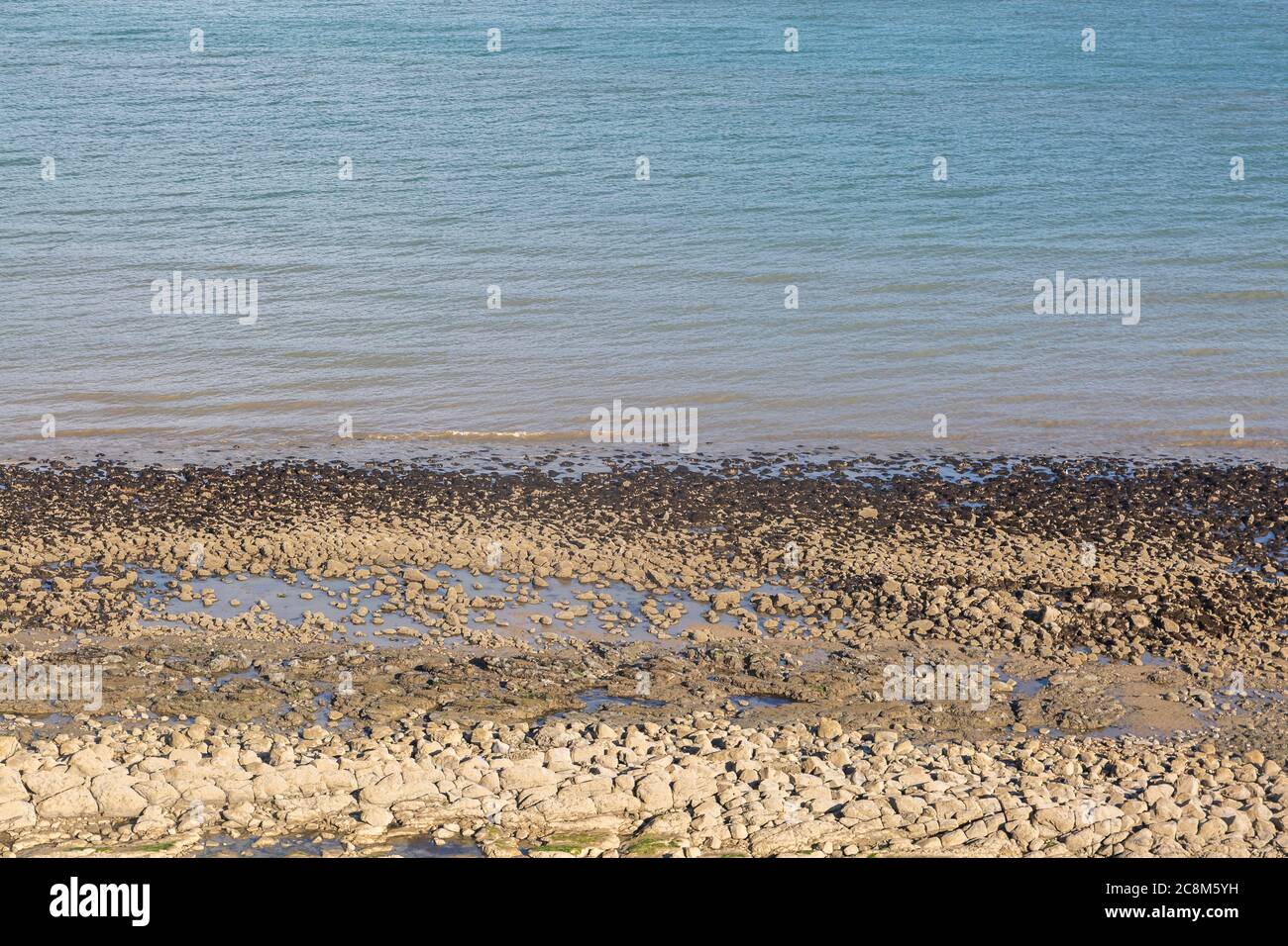 Looking down at pebbles and the sea, at low tide Stock Photo - Alamy