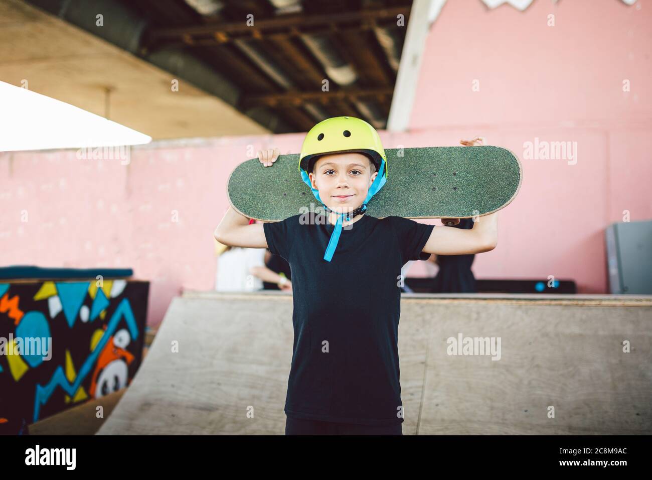 Caucasian child skateboarder posing with skate board on shoulders an ...