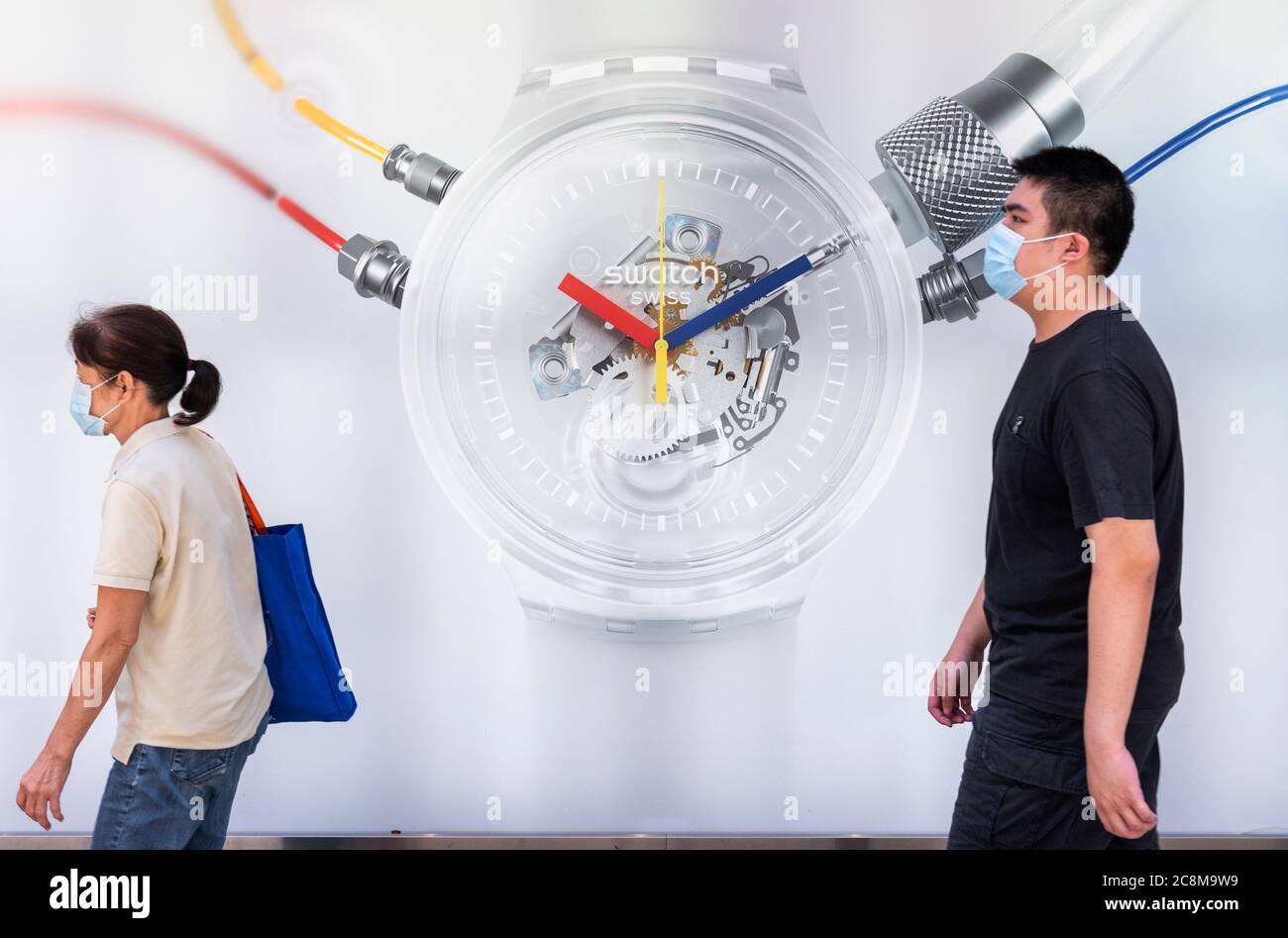 Pedestrians wearing face masks walk past a Swiss multinational ...