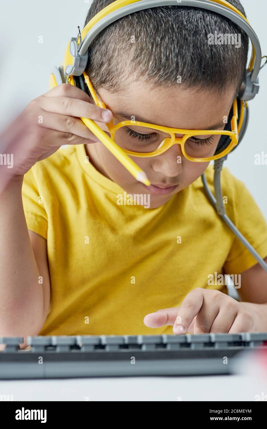 An adorable kid in a yellow t-shirt with a headphone listening online ...