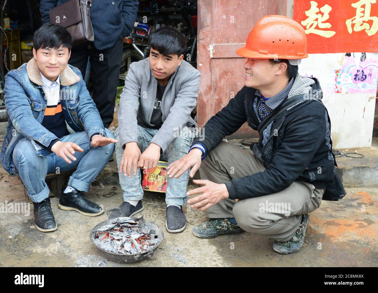 Chinese men using a small fire to warm up during the winter in Guizhou ...